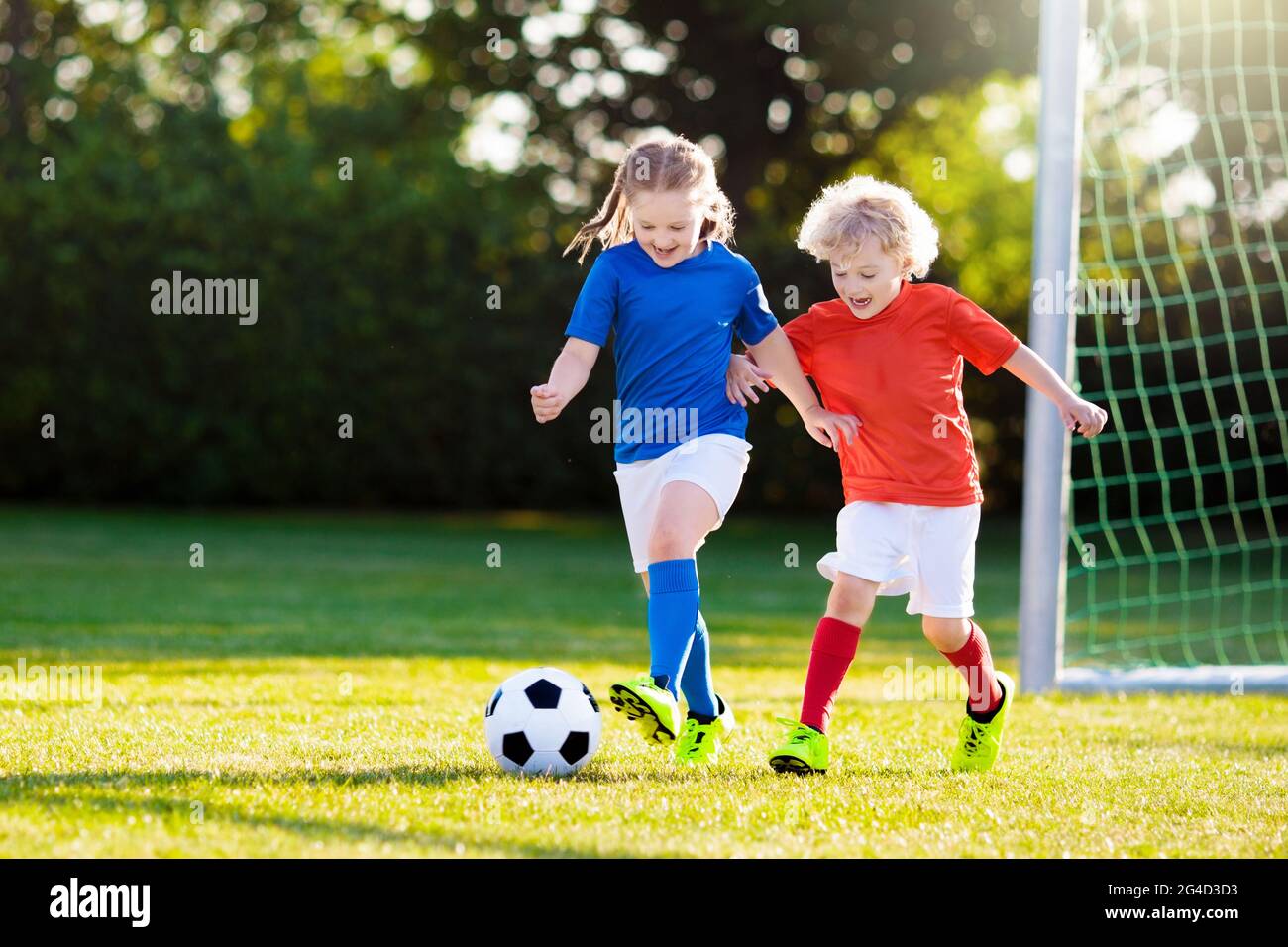 Kids play football on outdoor field. Children score a goal at soccer ...