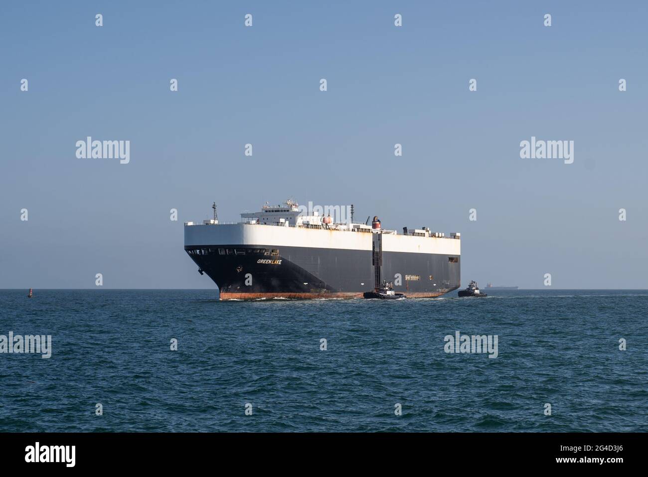 Cargo ship with tug boats Stock Photo - Alamy