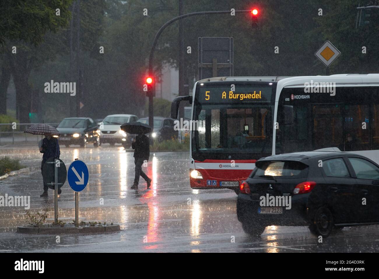 Hamburg, Germany. 21st June, 2021. Two pedestrians with umbrellas cross ...