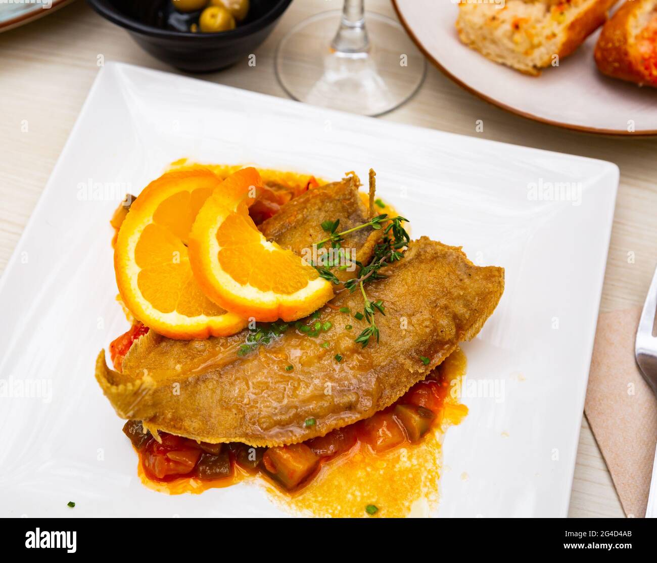 Black sole fish with stewed vegetables and orange Stock Photo - Alamy