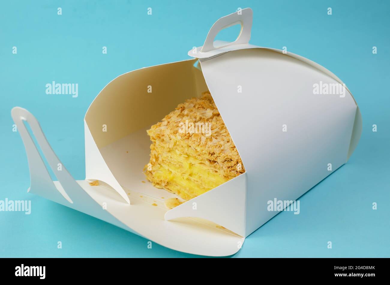 The cake is packaged in a white paper box on a light blue background ...