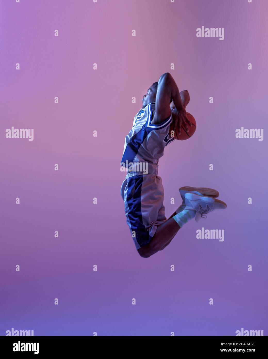 Basketball player jumping with ball in studio Stock Photo - Alamy