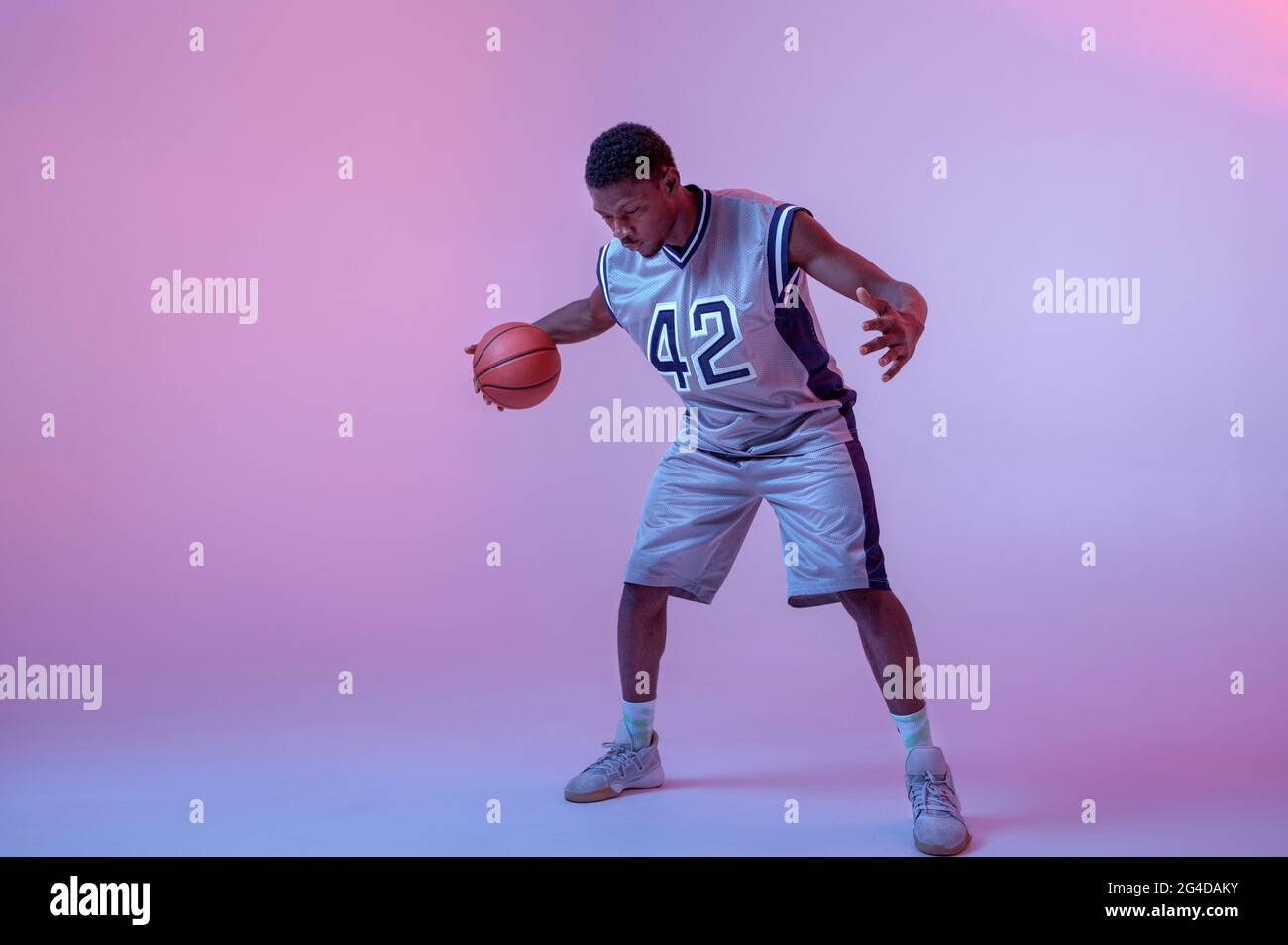 Basketball player practicing with ball in studio Stock Photo - Alamy