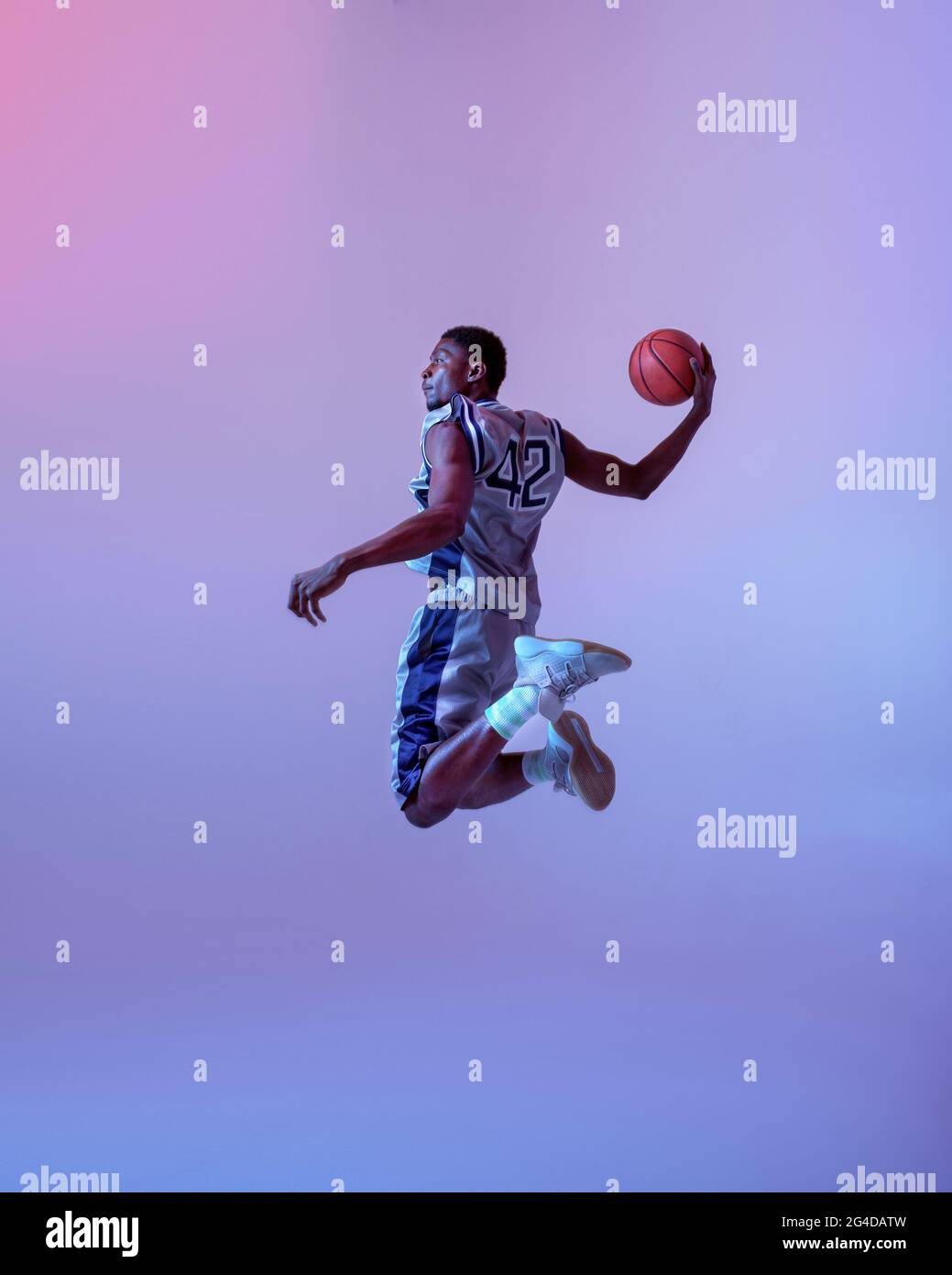 Basketball player jumping with ball in studio Stock Photo - Alamy