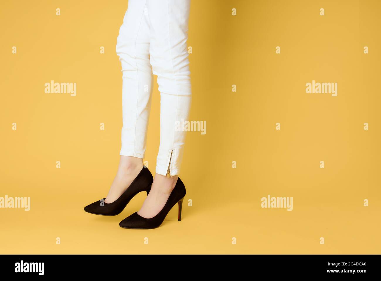 female inverted legs in black shoes cropped view yellow background ...