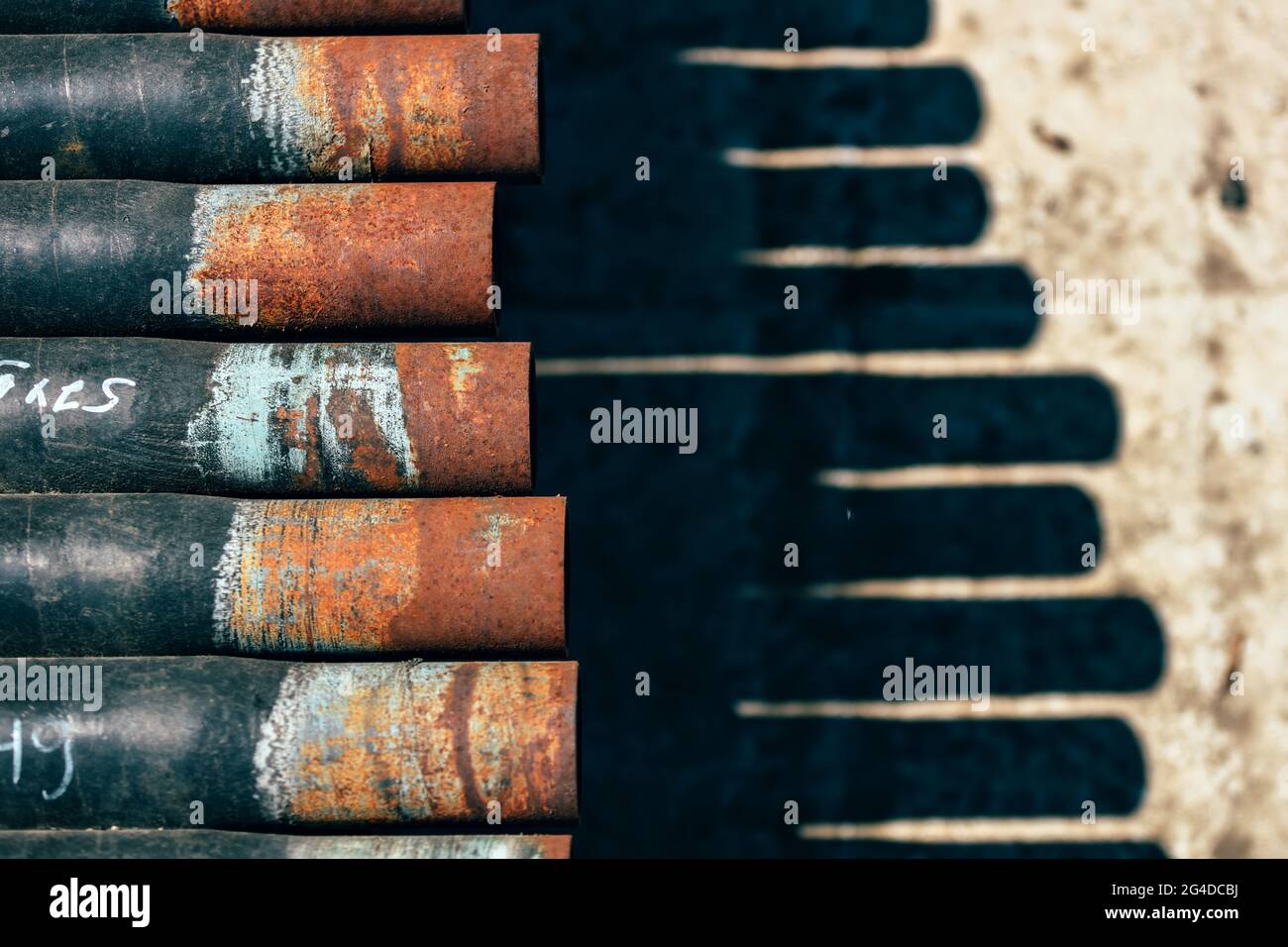 Round metal pipes lie in a row on a summer day. The shadow of the round ...