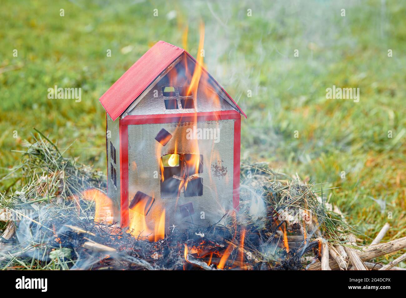 A cardboard house and grass is engulfed in flames. The concept of a ...