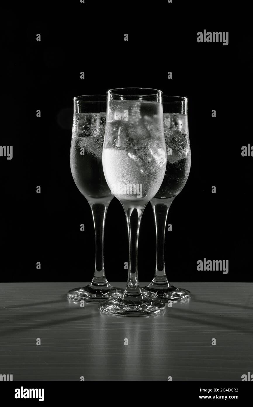 A refreshing, cold drink in glasses with ice on a black background ...