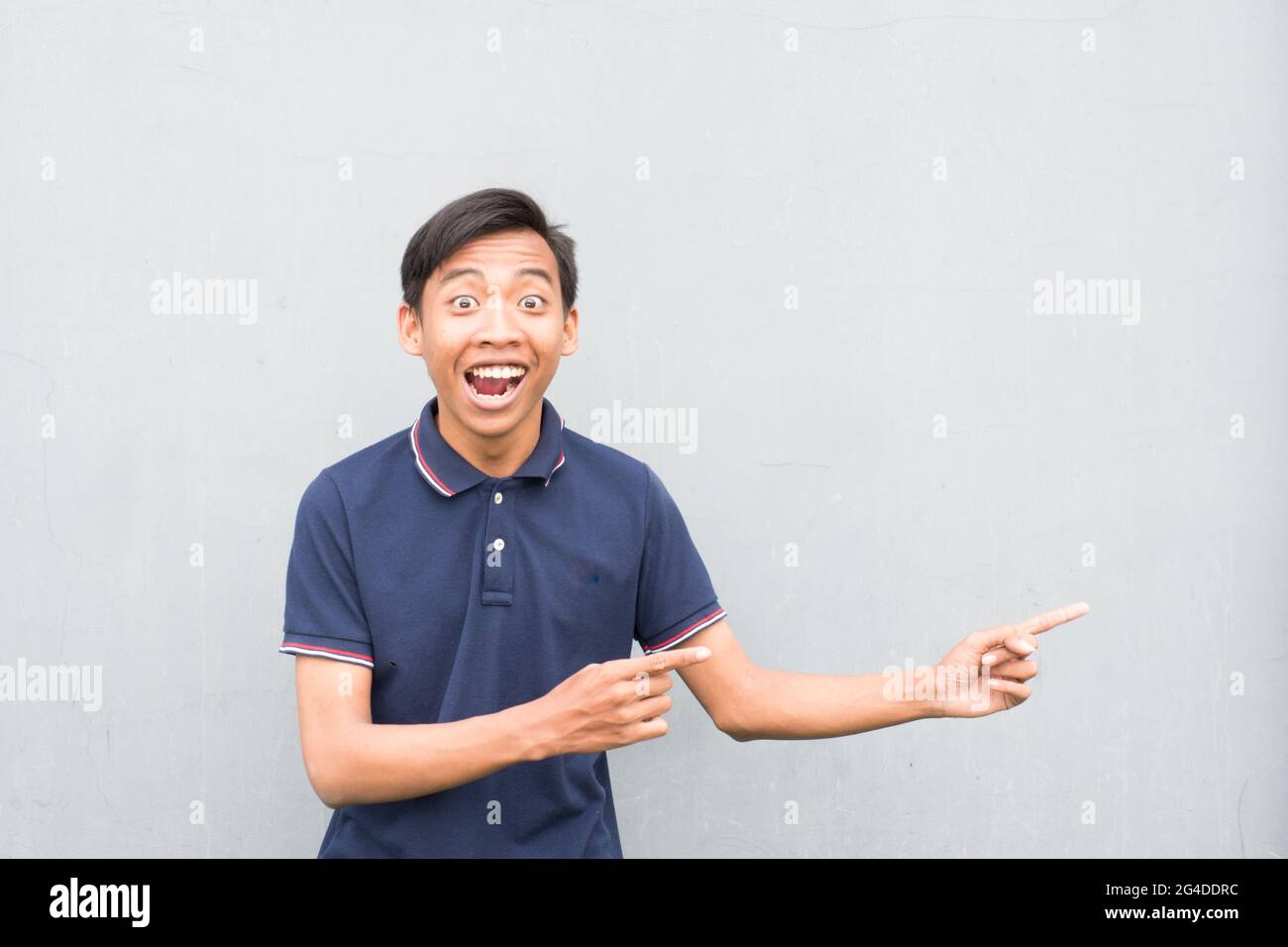 Happy Indonesian guy pointing his index fingers to the right on a white ...