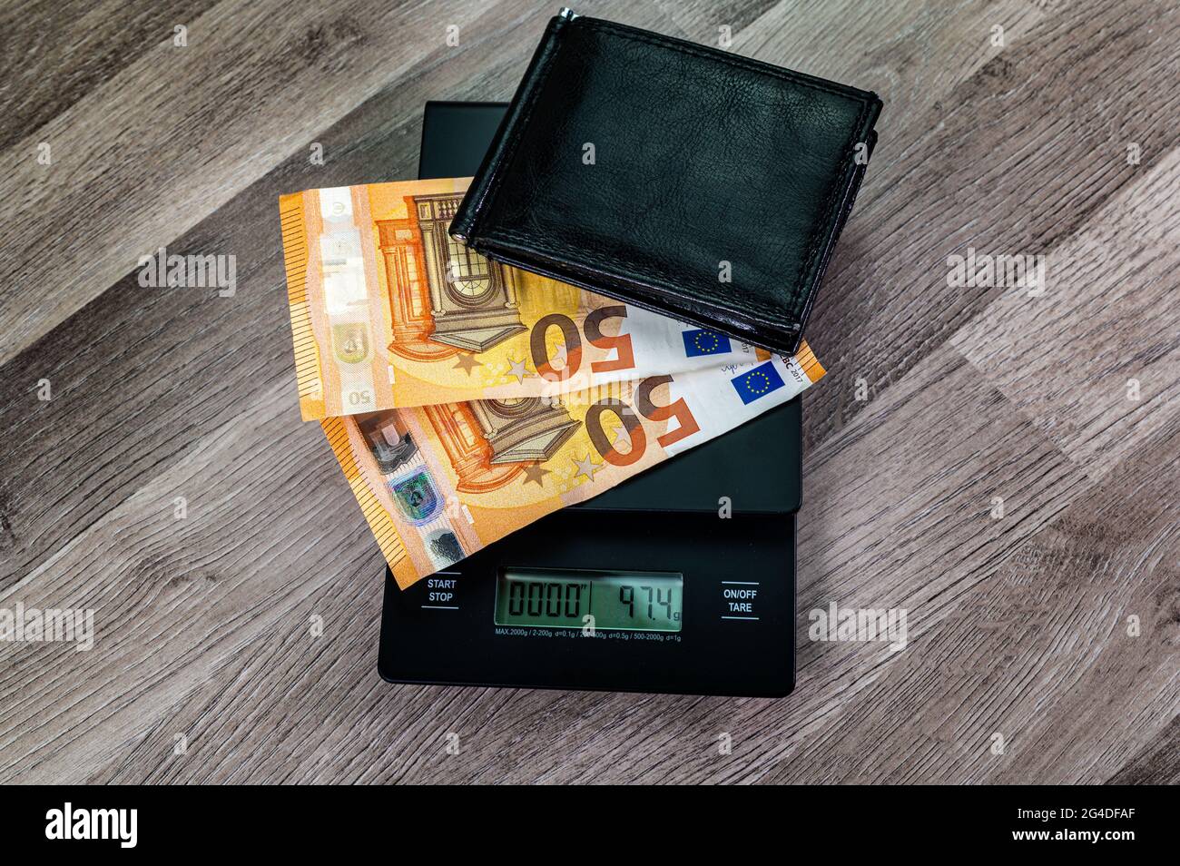 euro banknotes on top of a scale with portafolio on a wooden table ...