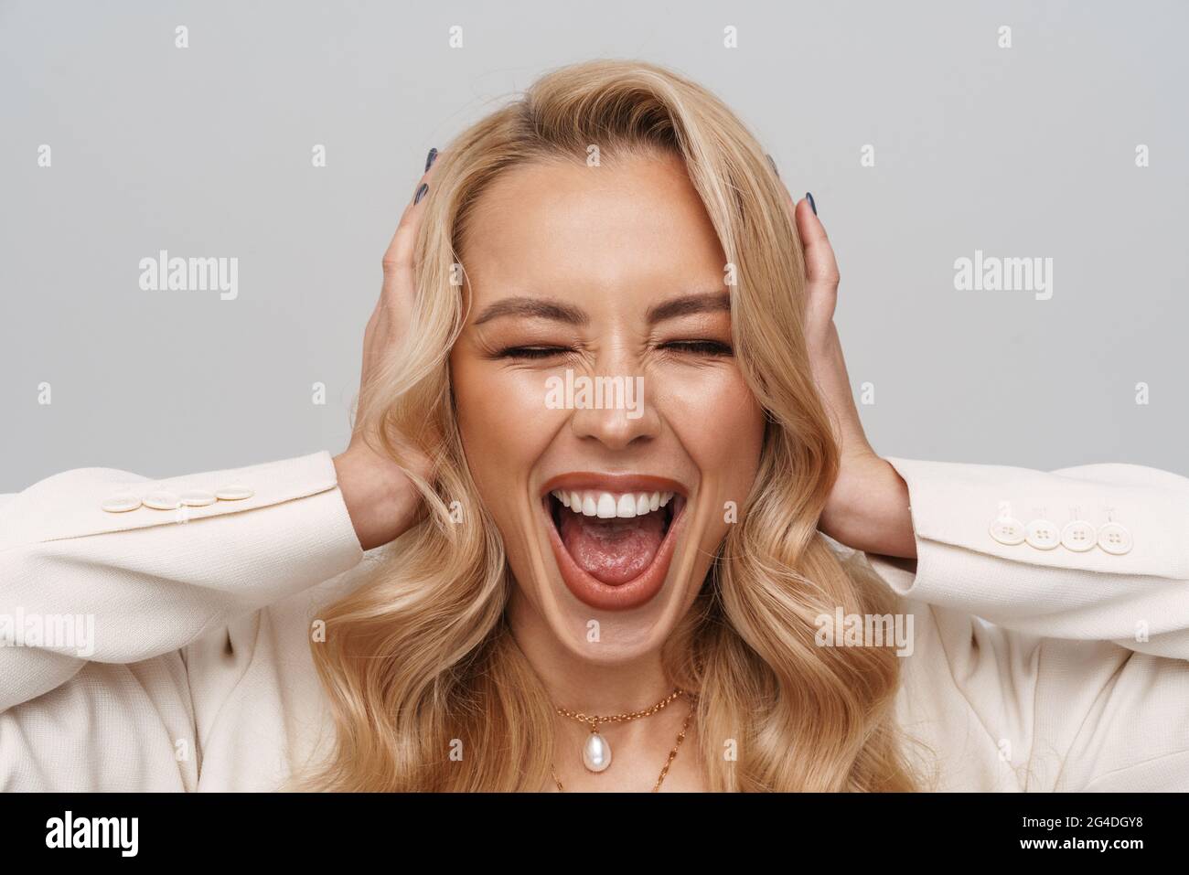 Beautiful excited girl in jacket screaming while grabbing her head ...
