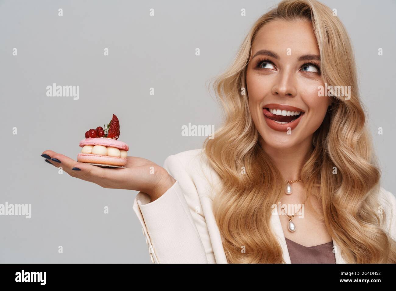 Happy gorgeous woman smiling while posing with cake isolated over grey ...