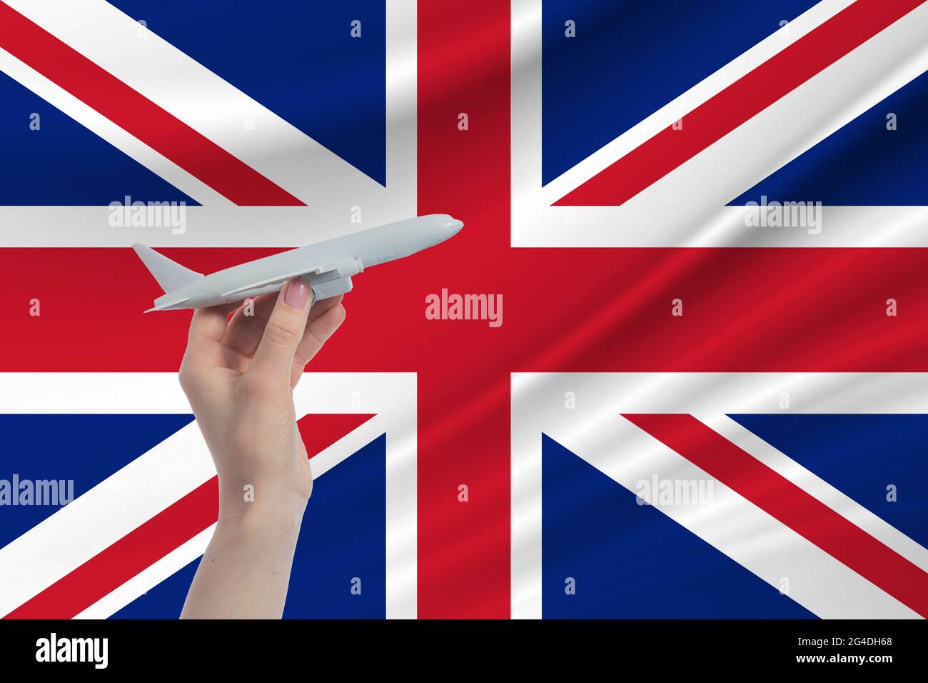 Airplane in hand with national flag of United Kingdom. Travel to United ...