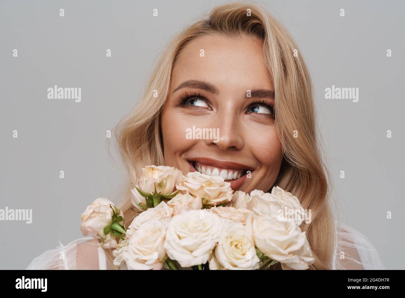 Beautiful happy smiling while posing with roses isolated over grey ...