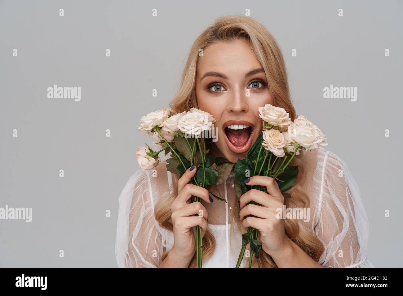 Beautiful excited girl exclaiming while posing with roses isolated over ...
