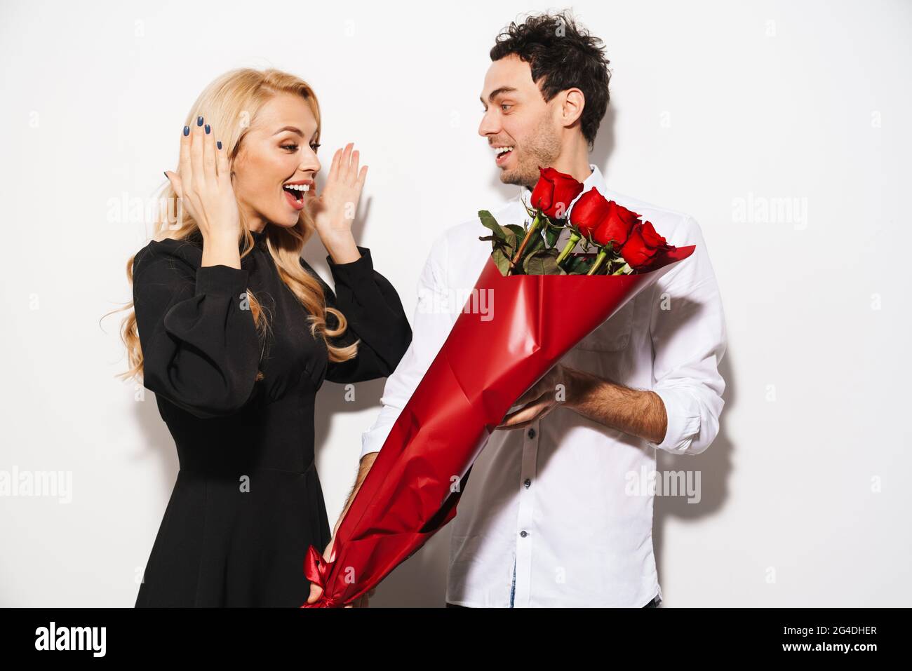 Happy man smiling and giving red roses to his excited girlfriend ...