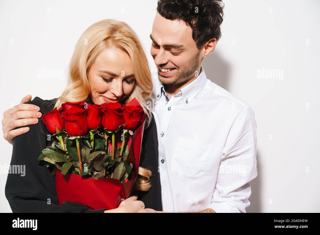 Happy romantic couple hugging while posing with red roses isolated over ...