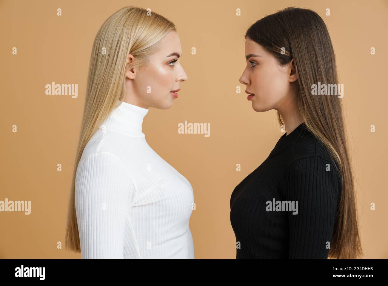 Beautiful two women looking at each other while posing on camera ...