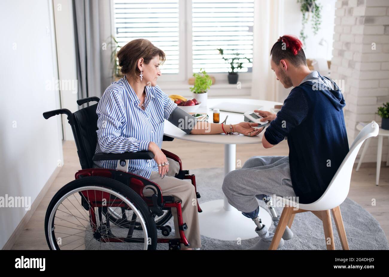 Disabled people in wheelchair sitting at the table indoors at home ...