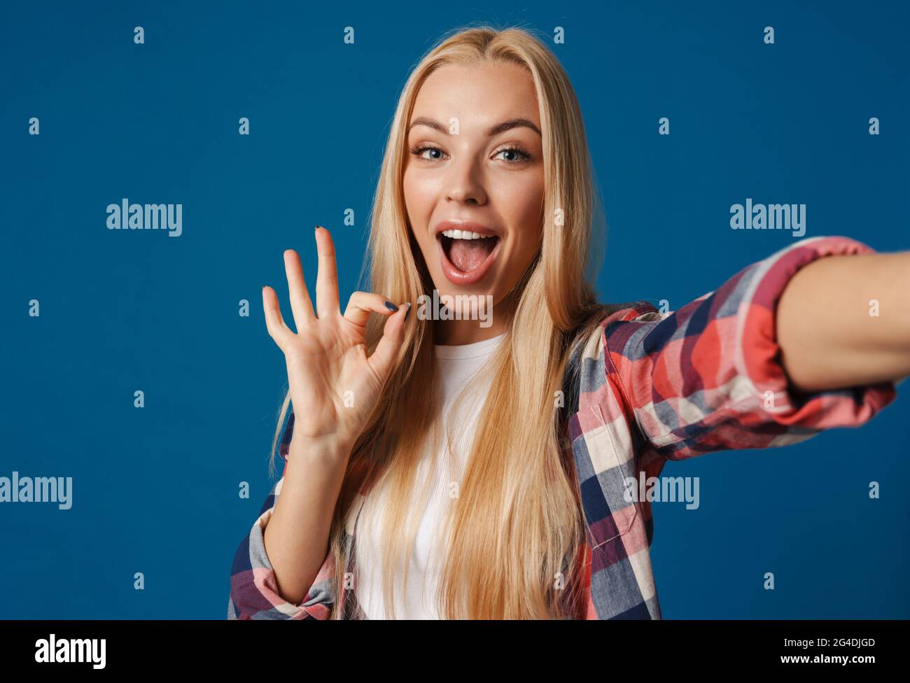 Happy blonde girl showing ok sign while taking selfie photo isolated ...