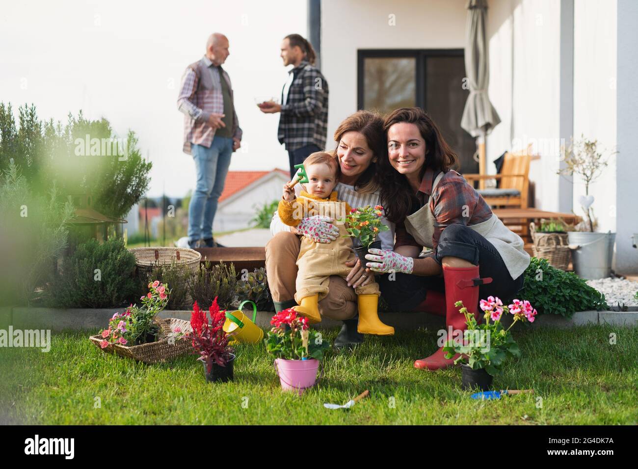 Happy multigeneration family outdoors planting flowers in garden at ...