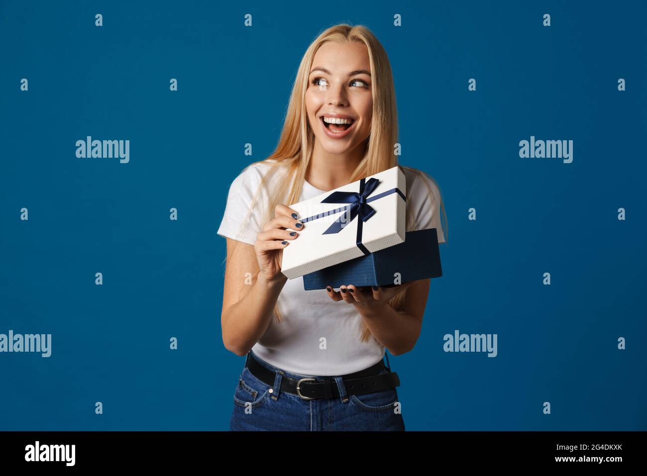 Excited beautiful girl smiling while opening gift box isolated over ...