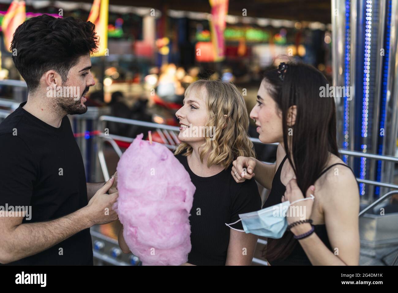 Group of friends eating cotton candy and having fun at an amusement ...