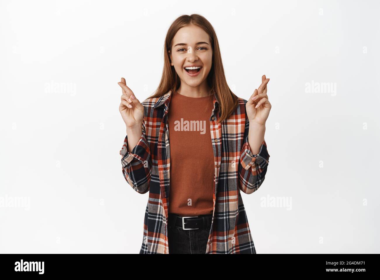 Portrait of hopeful girl makes her wish, look happy and smiling, cross ...