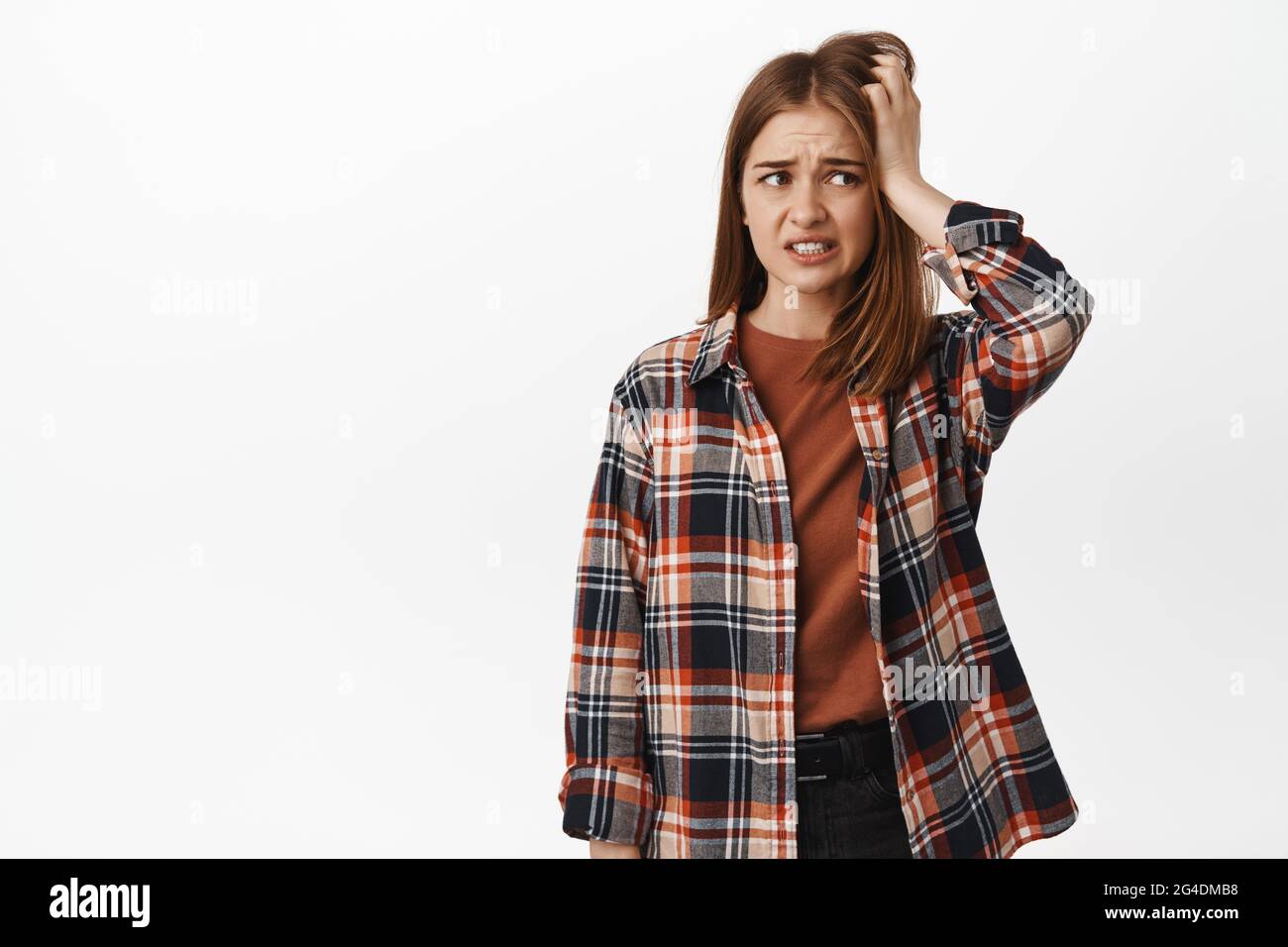 Worried and anxious blond girl scratch head, looking aside and ...