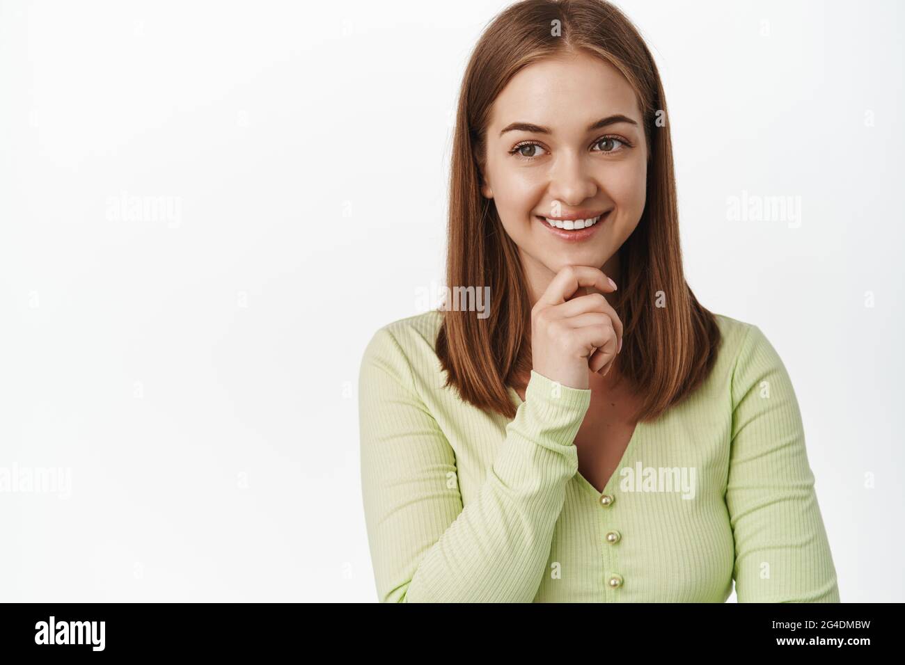Close up of thoughtful young successful woman, smiling pleased, looking ...