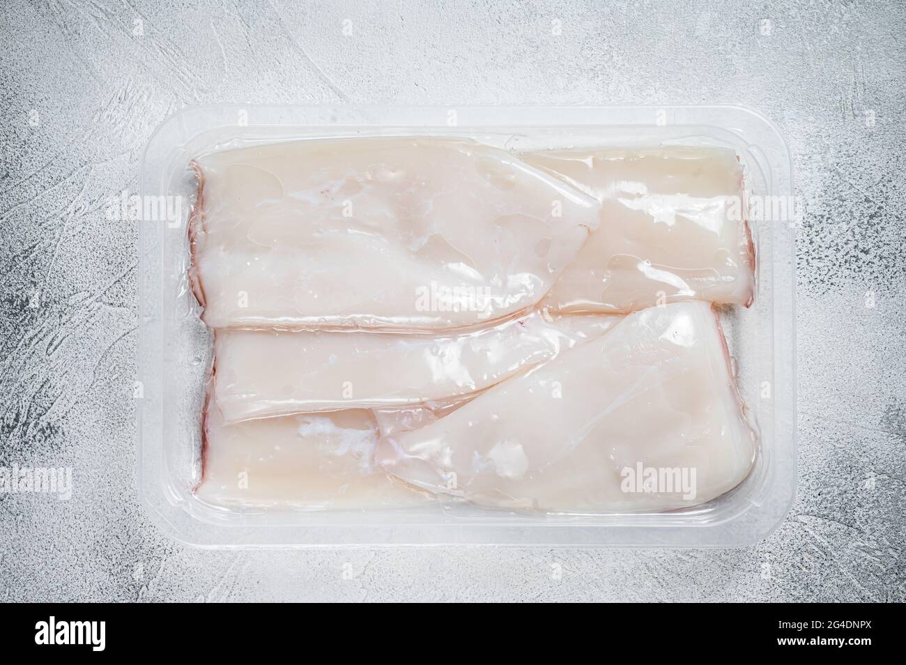 Fresh Raw Squid or Calamari in a vacuum package on a kitchen table ...
