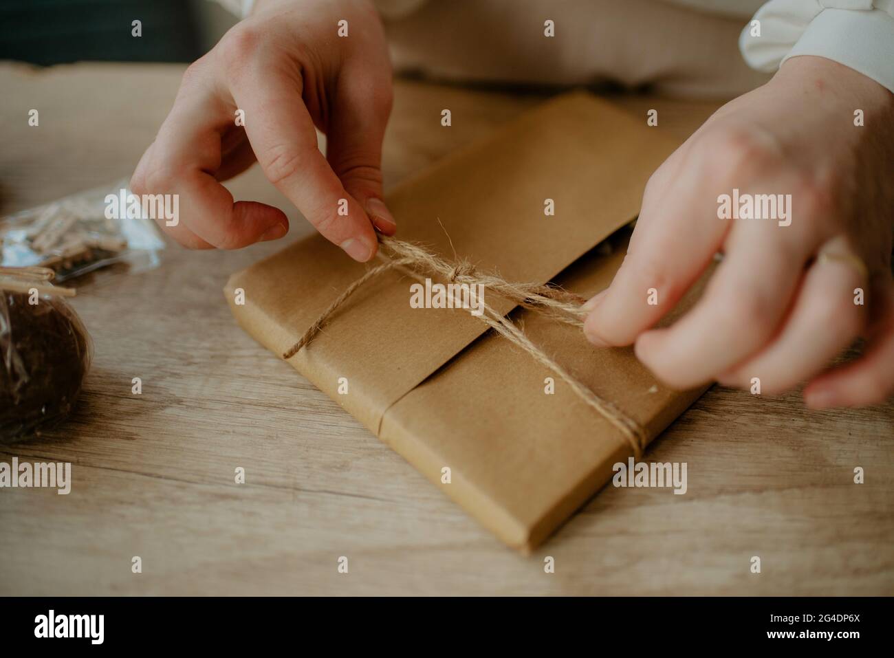 Woman tying a knot to wrap a book as birthday gift - rustic theme Stock ...