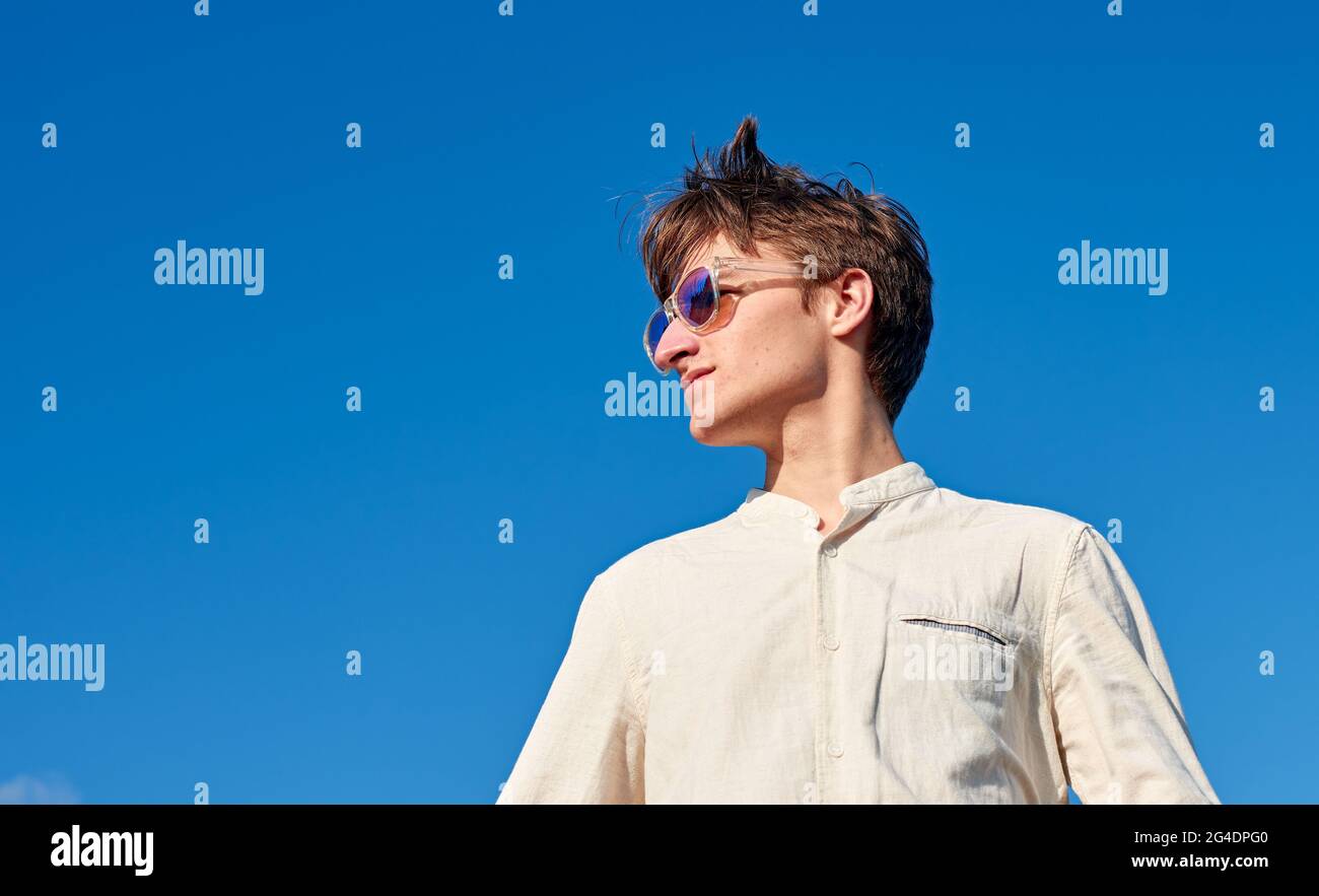 Low angle of a young handsome Spanish male wearing sunglasses against ...