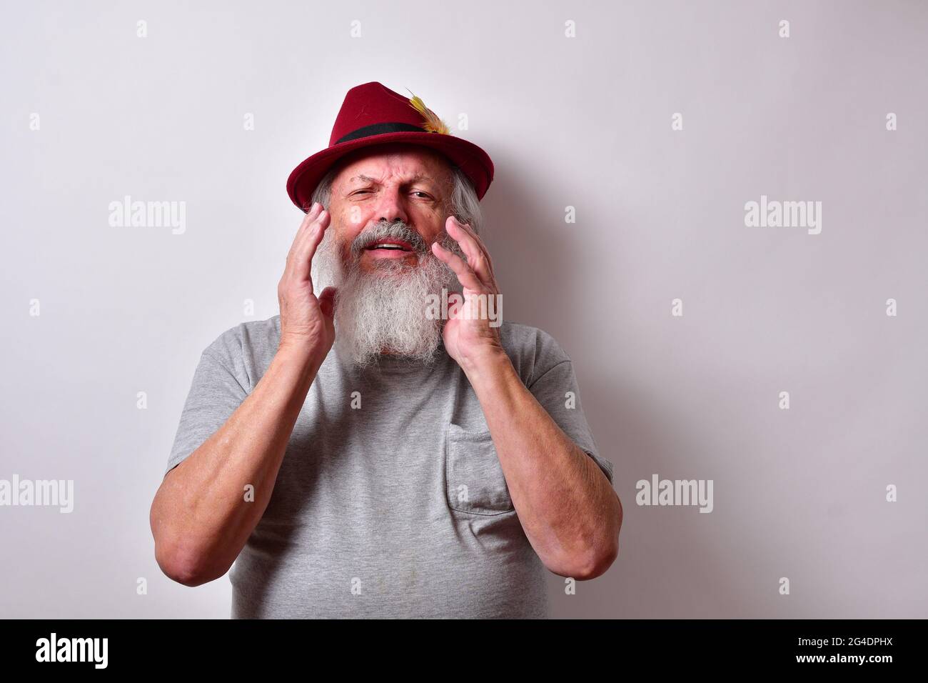 Old American male with a grey shirt and red fedora hat in a dramatic ...