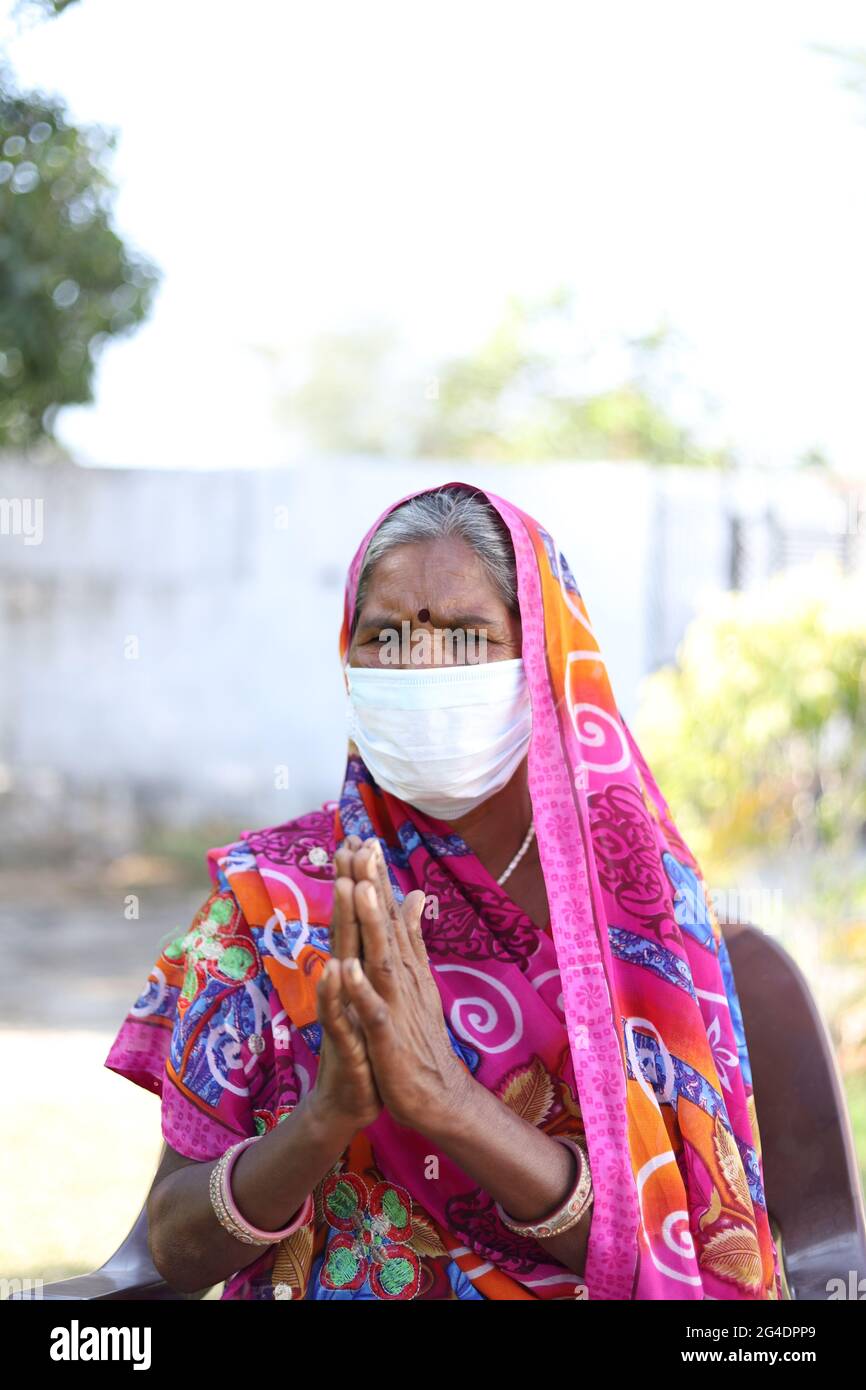Closeup shot of an Indian woman with a traditional dress and white mask ...