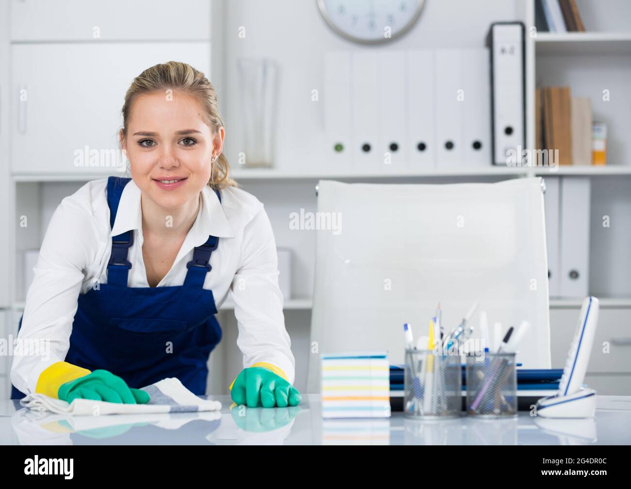 Workwoman wiping dust in office Stock Photo - Alamy