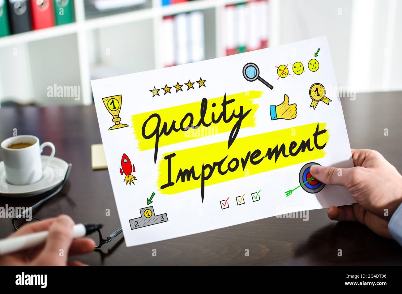Hand holding a paper showing quality improvement concept Stock Photo ...