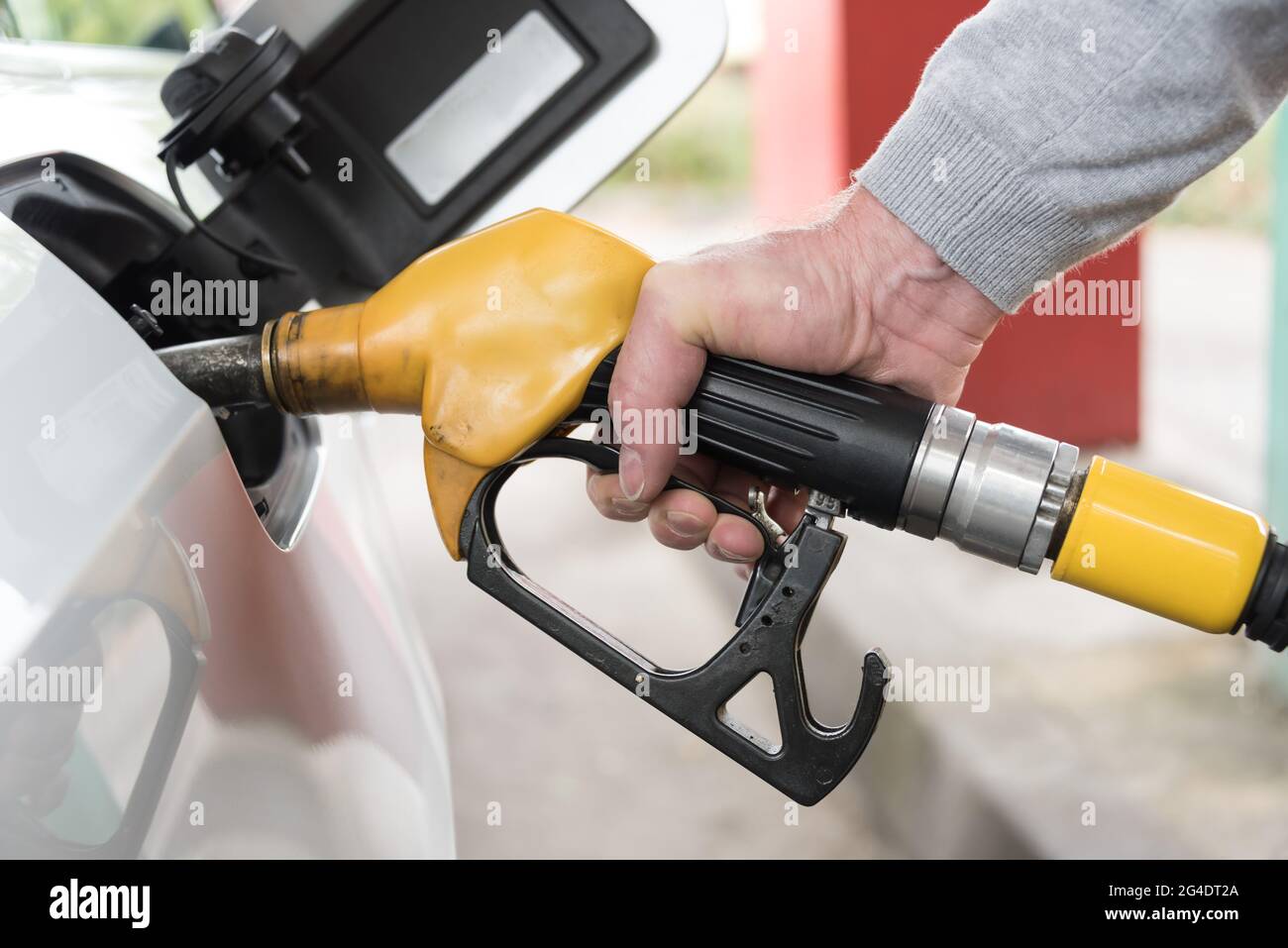 Hand holding yellow fuel pump nozzle and refilling car Stock Photo - Alamy
