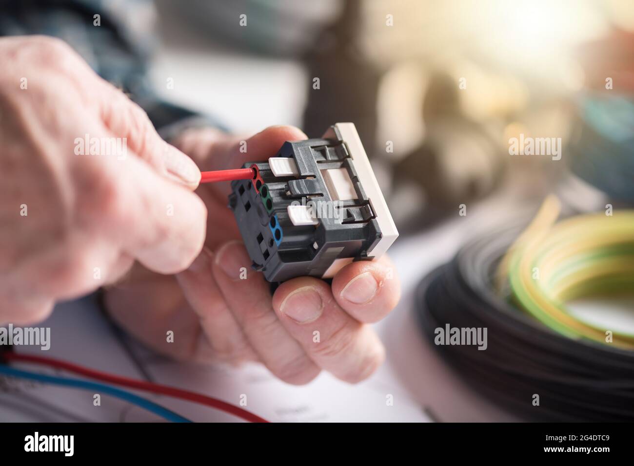 Electrician hands connecting a wire into a power socket, light effect ...