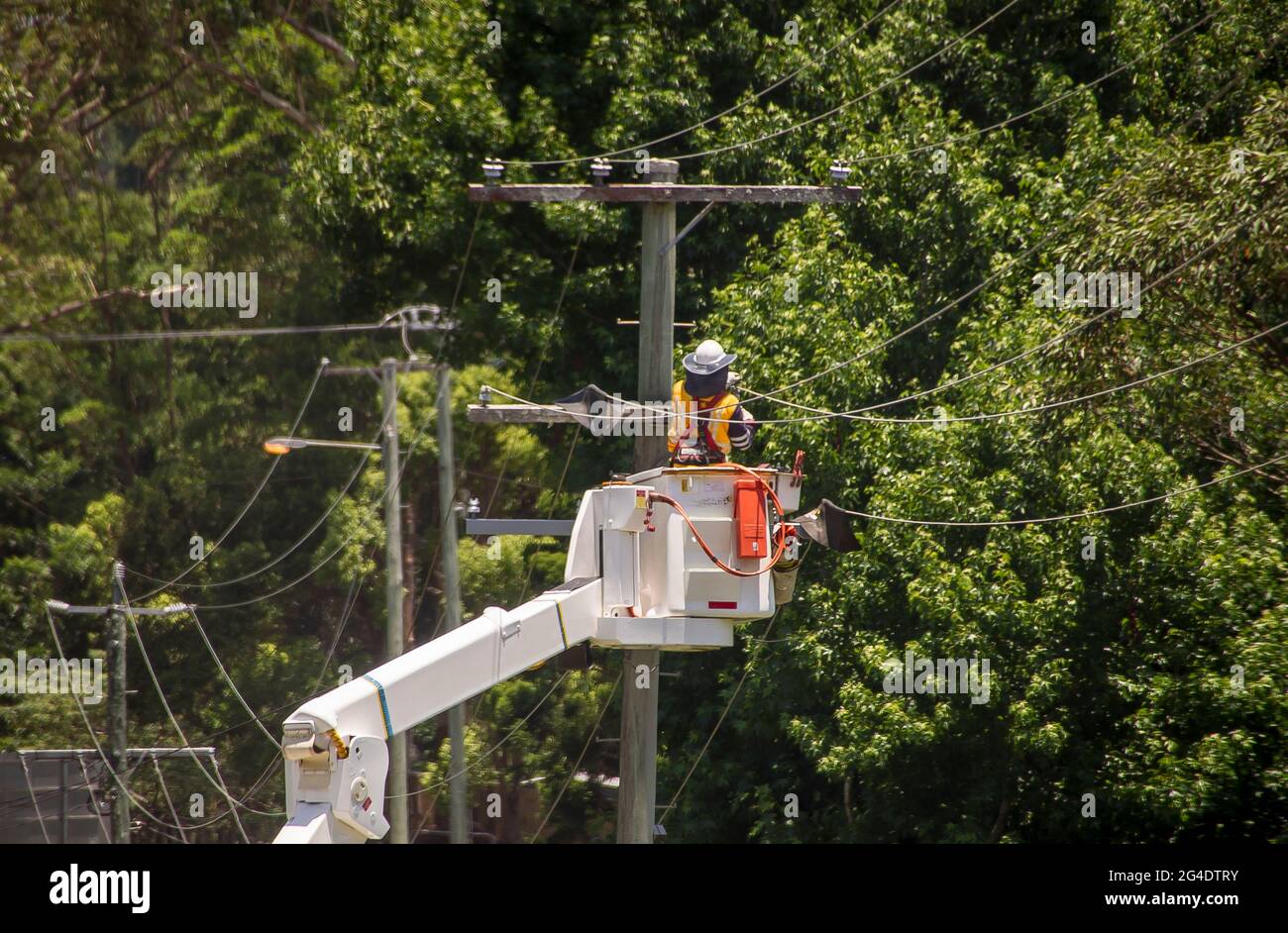 Linesman in cherry-picker working on overhead electric power cable and ...