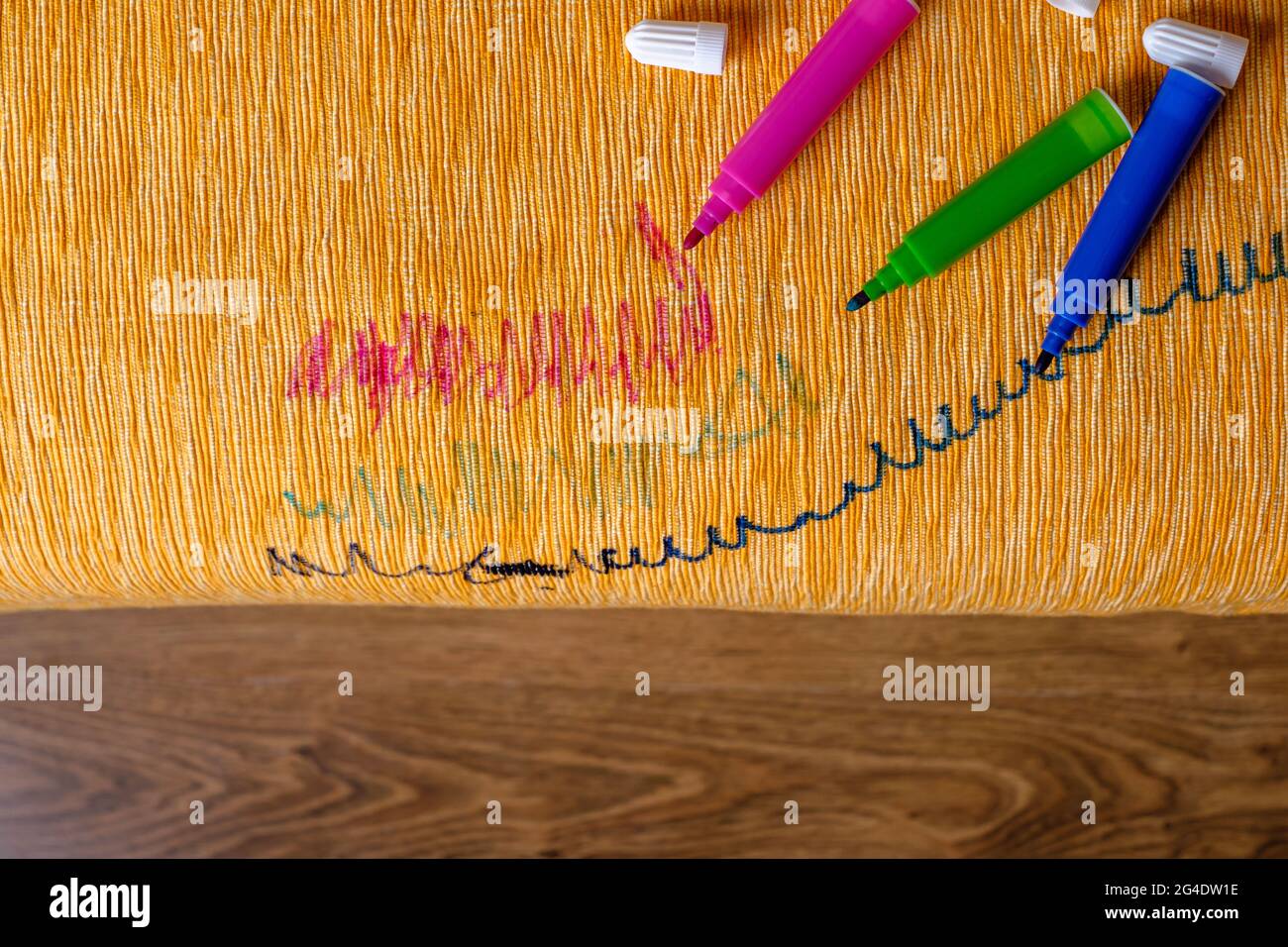 Dirty stains of felt-tip pens on the yellow upholstery of the couch ...