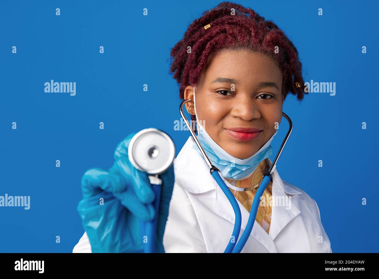 Portrait of african female doctor in lab coat with face mask and ...