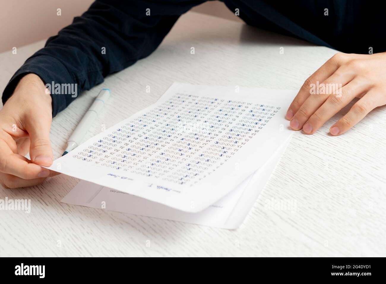 close up person's hands writing answers in the social test on a paper ...