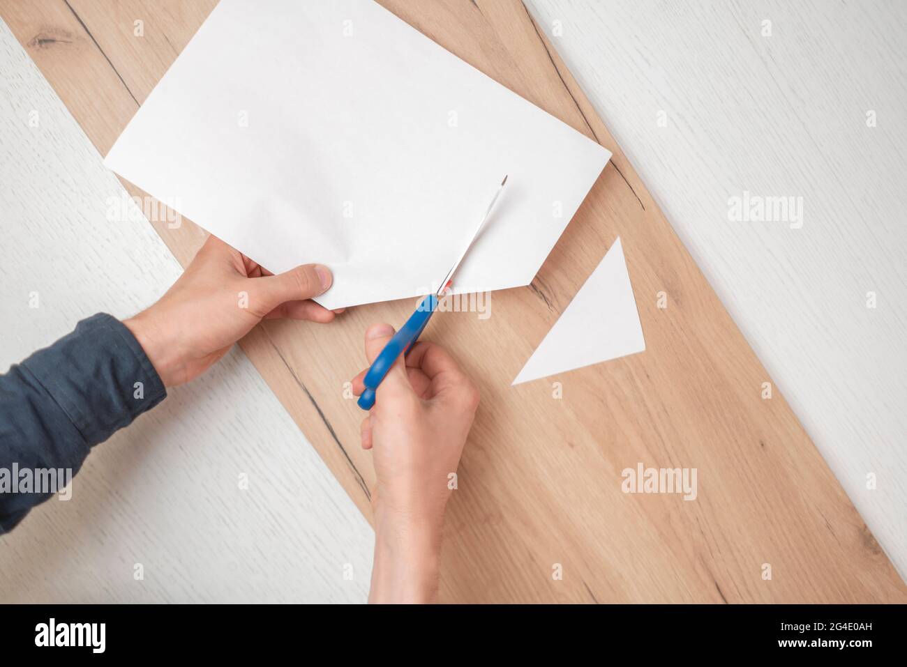 person's hands holding piece of paper sheet and cut it with scissors ...