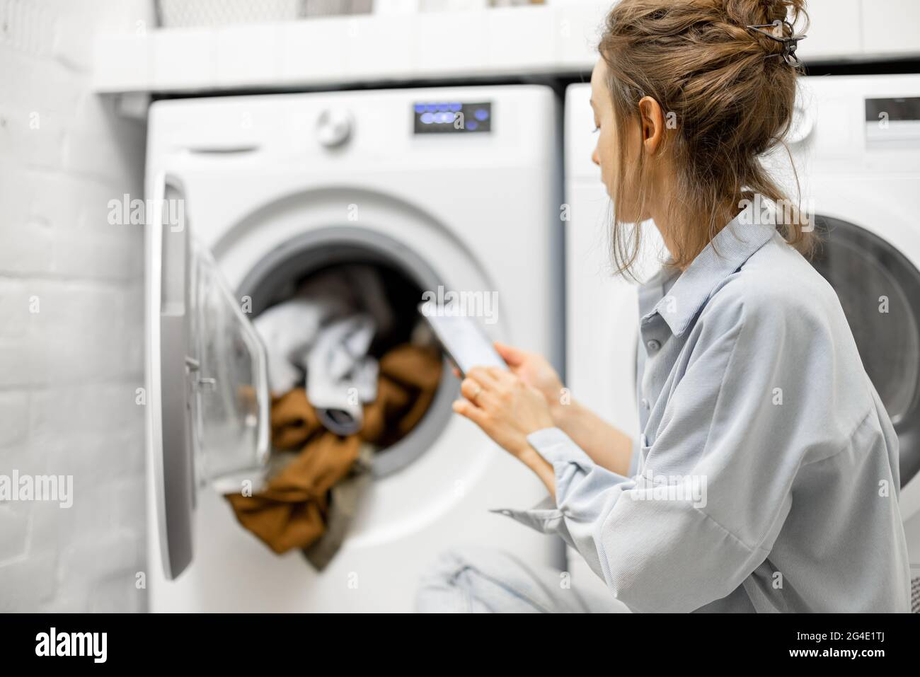 Woman controls washing machine with a smartphone Stock Photo - Alamy