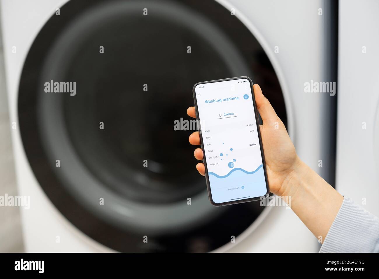 Woman controls washing machine with a smartphone Stock Photo - Alamy