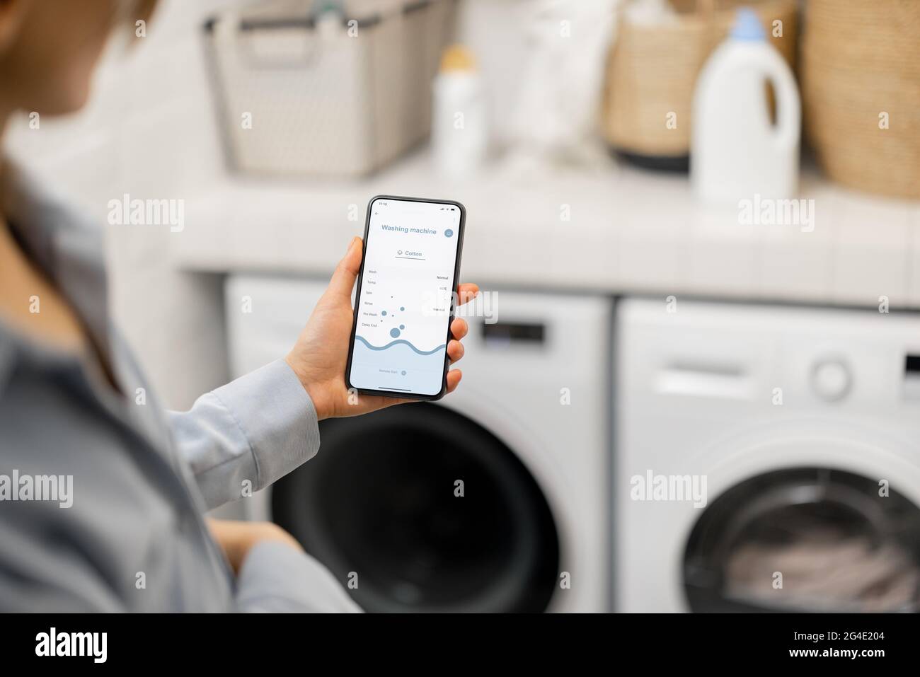 Woman controls washing machine with a smartphone Stock Photo - Alamy