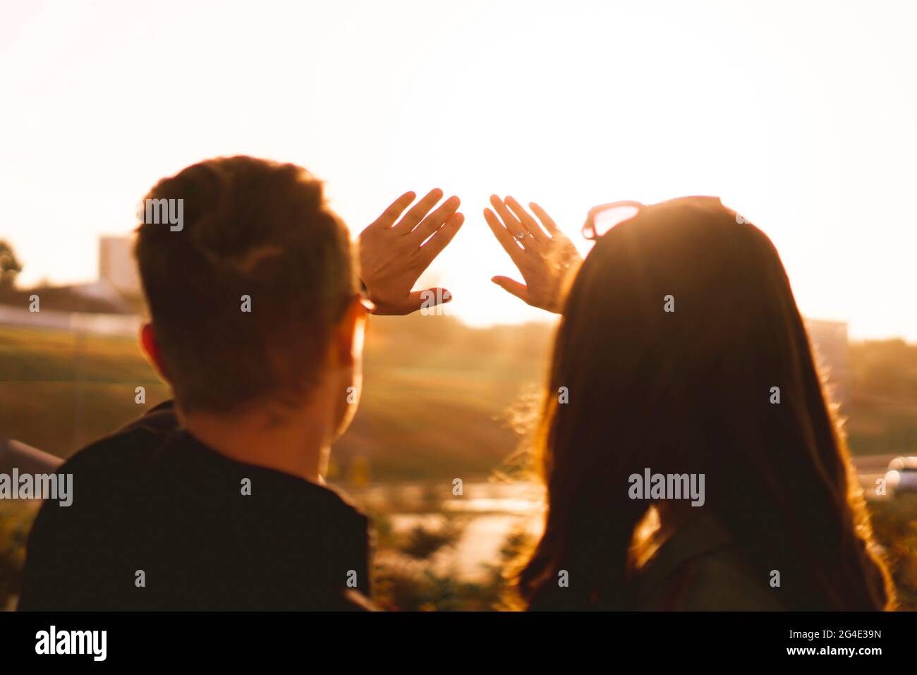 young couple of man and woman watching at the sky and cover the sun ...