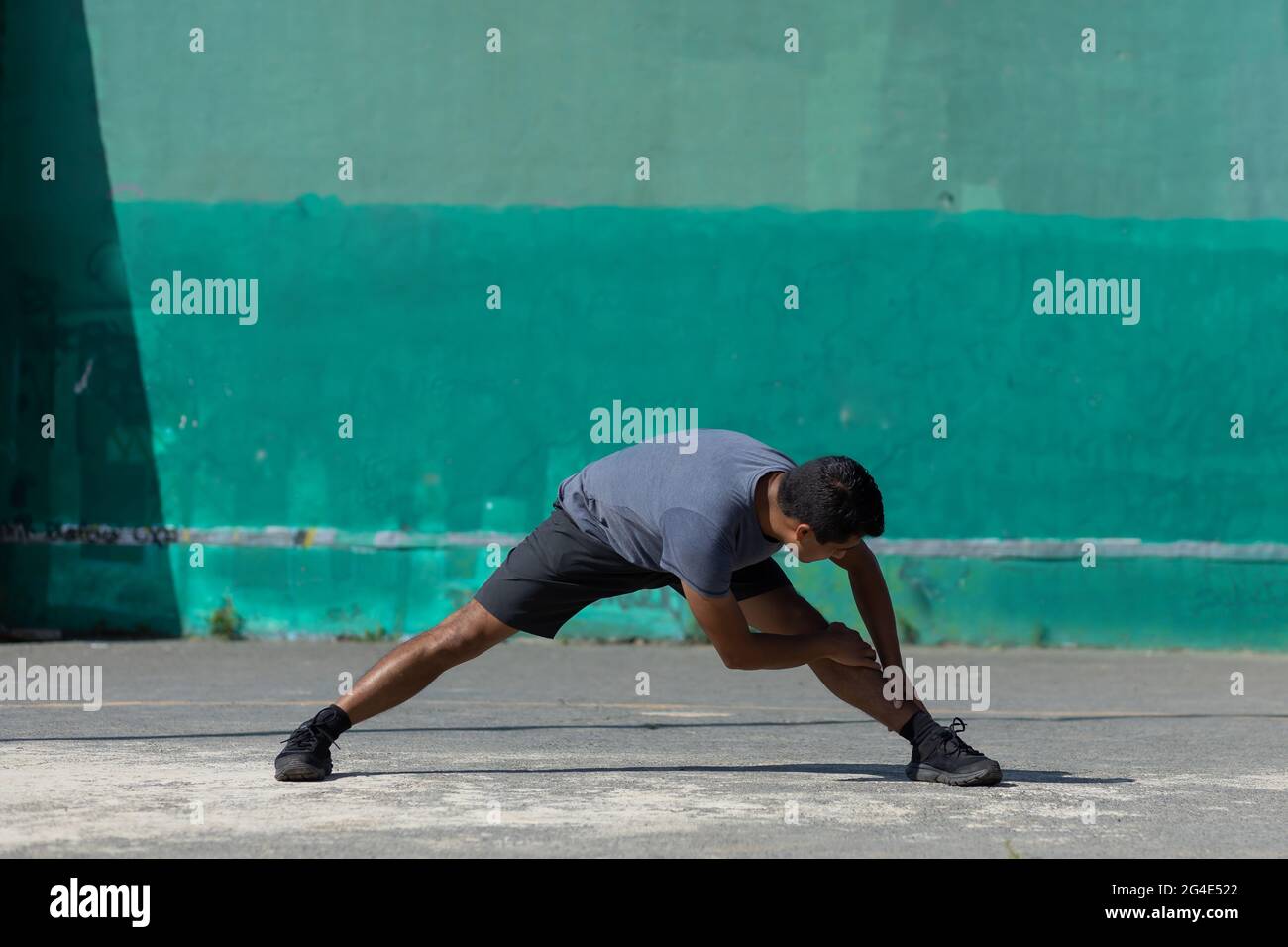 An athletic young male bending forward in the open air; urban exercise ...