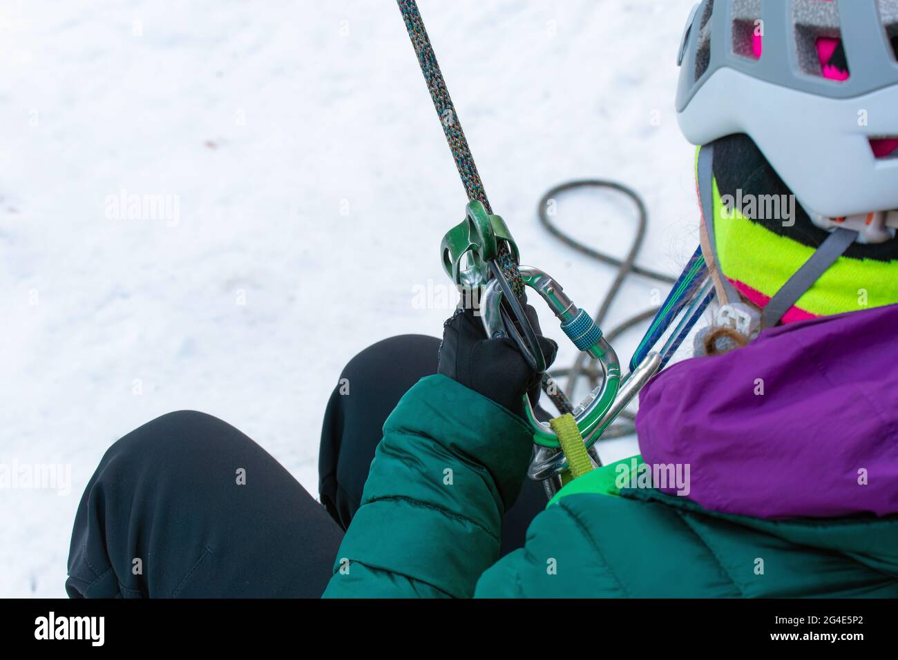 Woman controlling a safety top rope while other person climbs on a ...